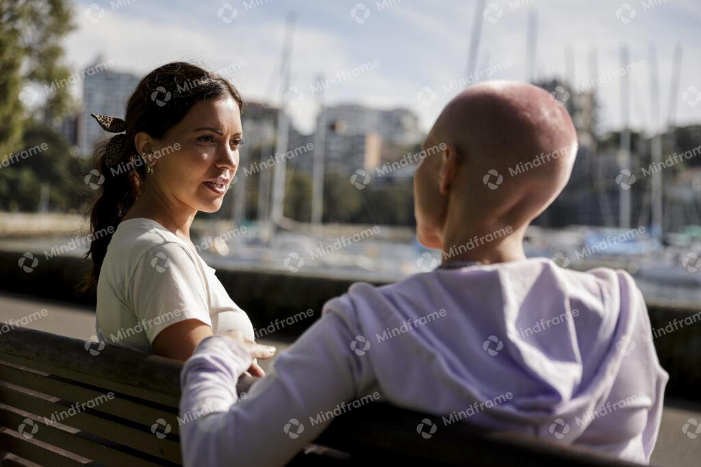 Two people talking, sitting on a bench near the water – Mindframe ...