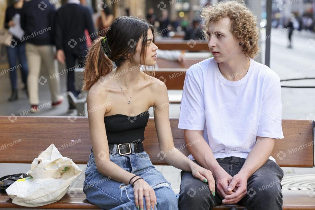 Two people talking while seated on a bench in an urban landscape ...
