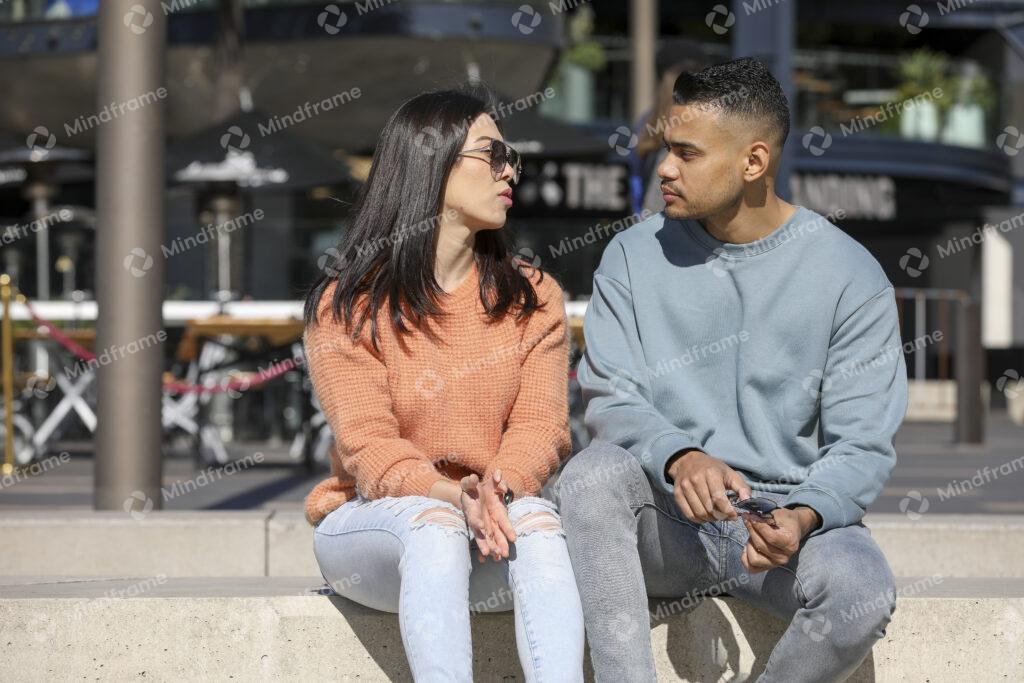 Two people sitting on a step and talking to each other outdoors ...
