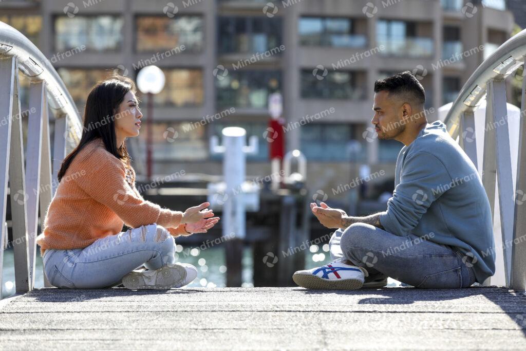 Two people sitting on a small bridge and talking to each other ...