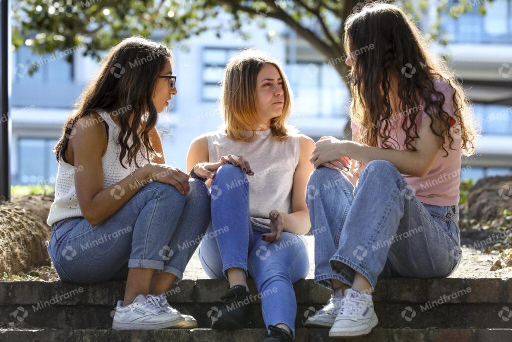 Group of young women sitting outside on steps talking – Mindframe ...