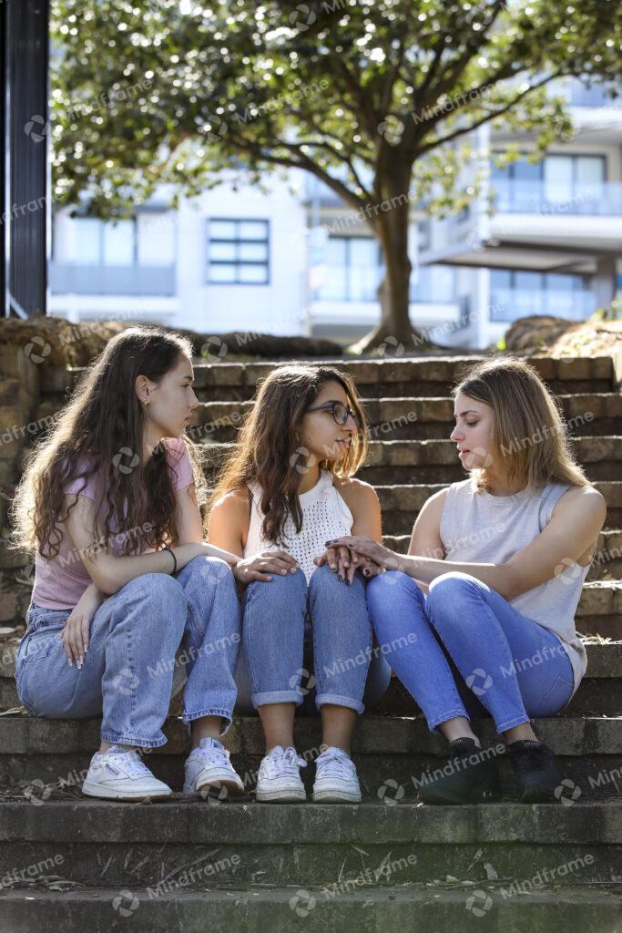 Group of young women sitting outside on steps talking – Mindframe ...
