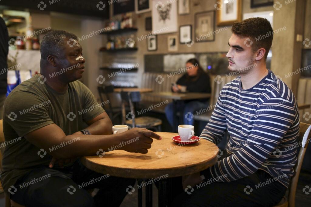 Two people sitting and talking indoors at a cafe – Mindframe online ...
