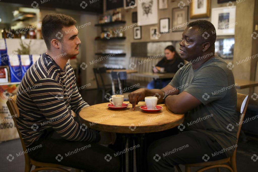 Two people sitting and talking indoors at a cafe – Mindframe online ...