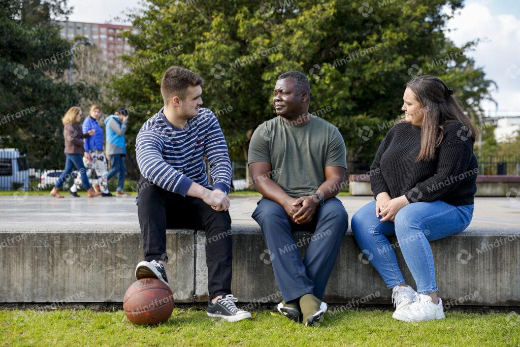 Three people talking, sitting outside – Mindframe online image collection