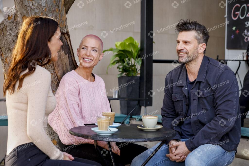Three people sitting outside talking at a cafe – Mindframe online image ...
